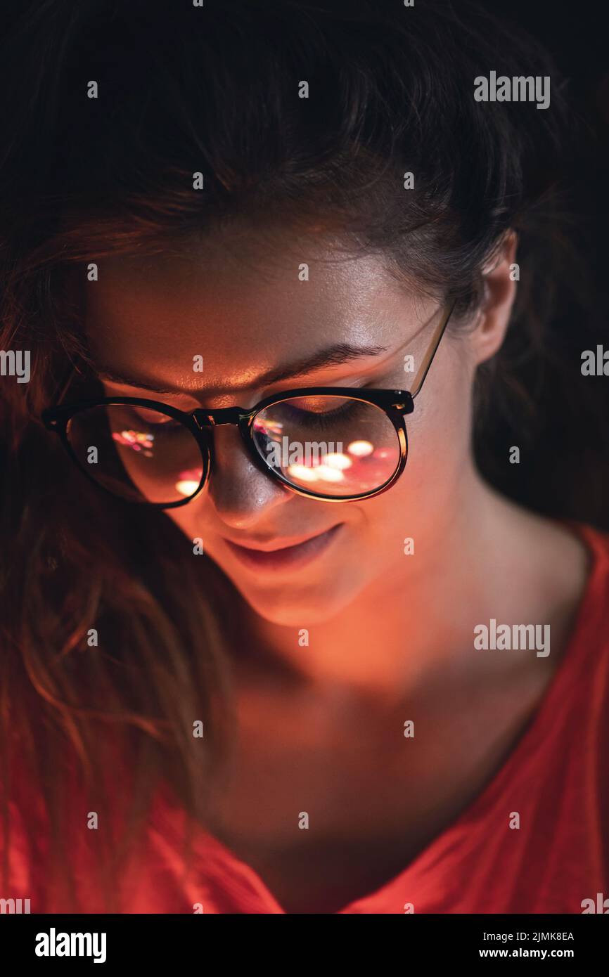 Young woman with reflection of glowing light balls in her eye glasses ...