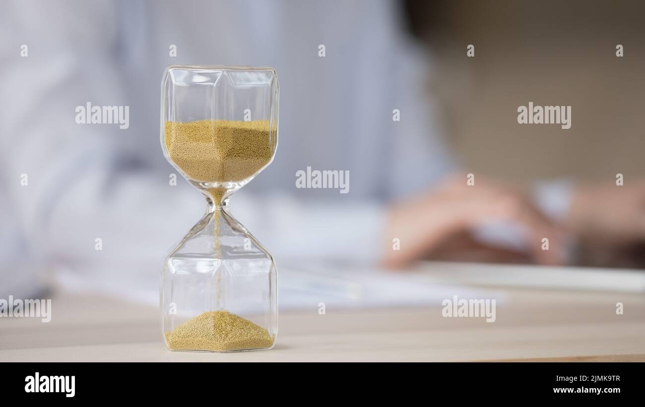 Sand watch object close up with hands typing on laptop Stock Photo - Alamy