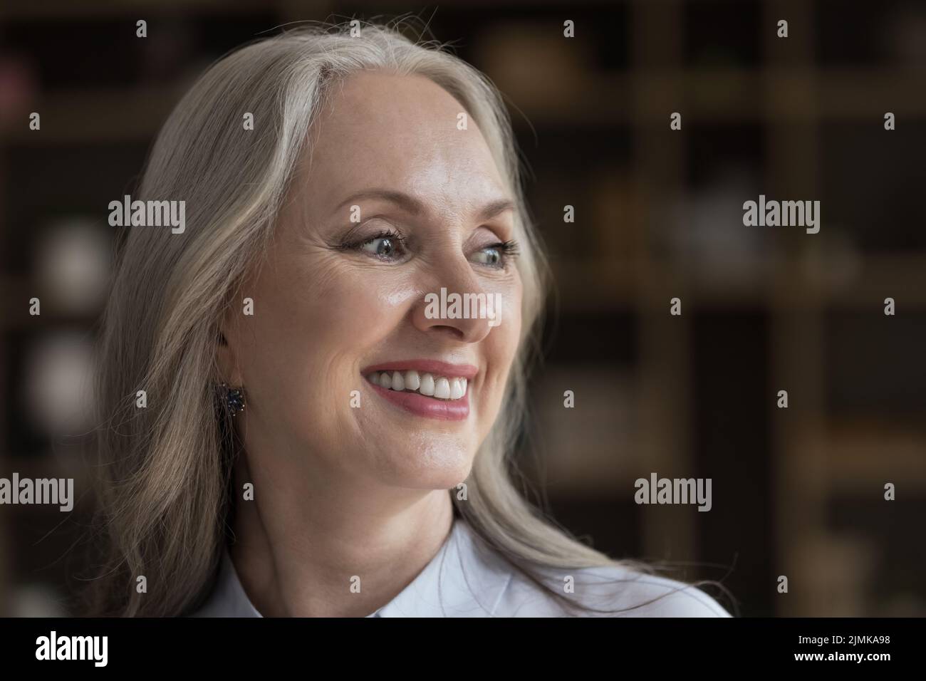 Happy senior lady looking away with thoughtful satisfied toothy smile ...