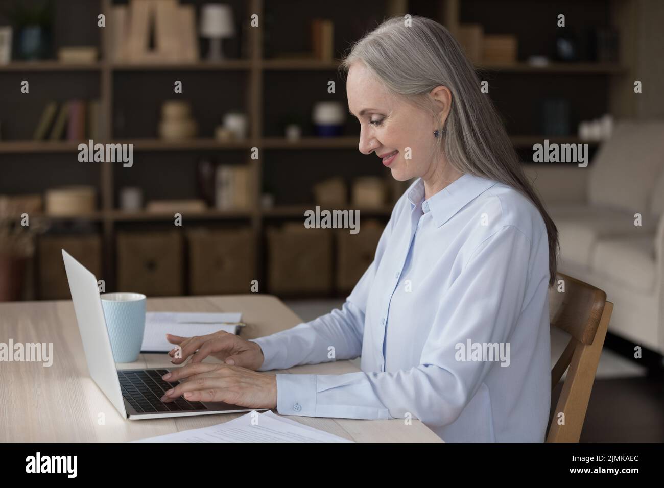 Happy elderly retired freelance business woman typing on laptop Stock ...