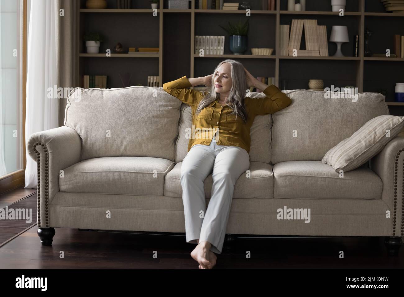 Thoughtful peaceful pretty elderly woman resting on soft couch Stock ...