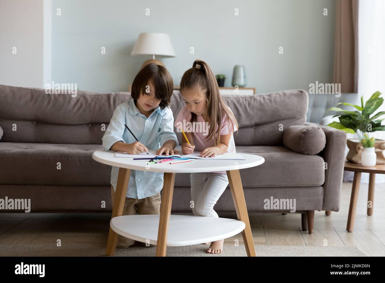 Cute siblings drawing pictures in sketchbook with pencils Stock Photo ...