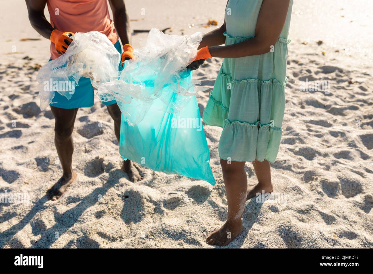 Low section of african american couple collecting plastic garbage in ...