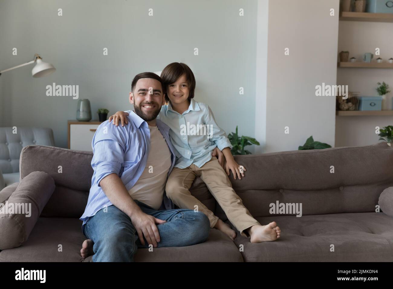 Son hugs father sit on sofa smile look at camera Stock Photo - Alamy