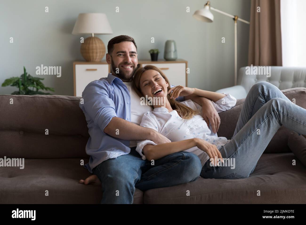 Couple relaxing on sofa laughing look at camera feel happy Stock Photo ...