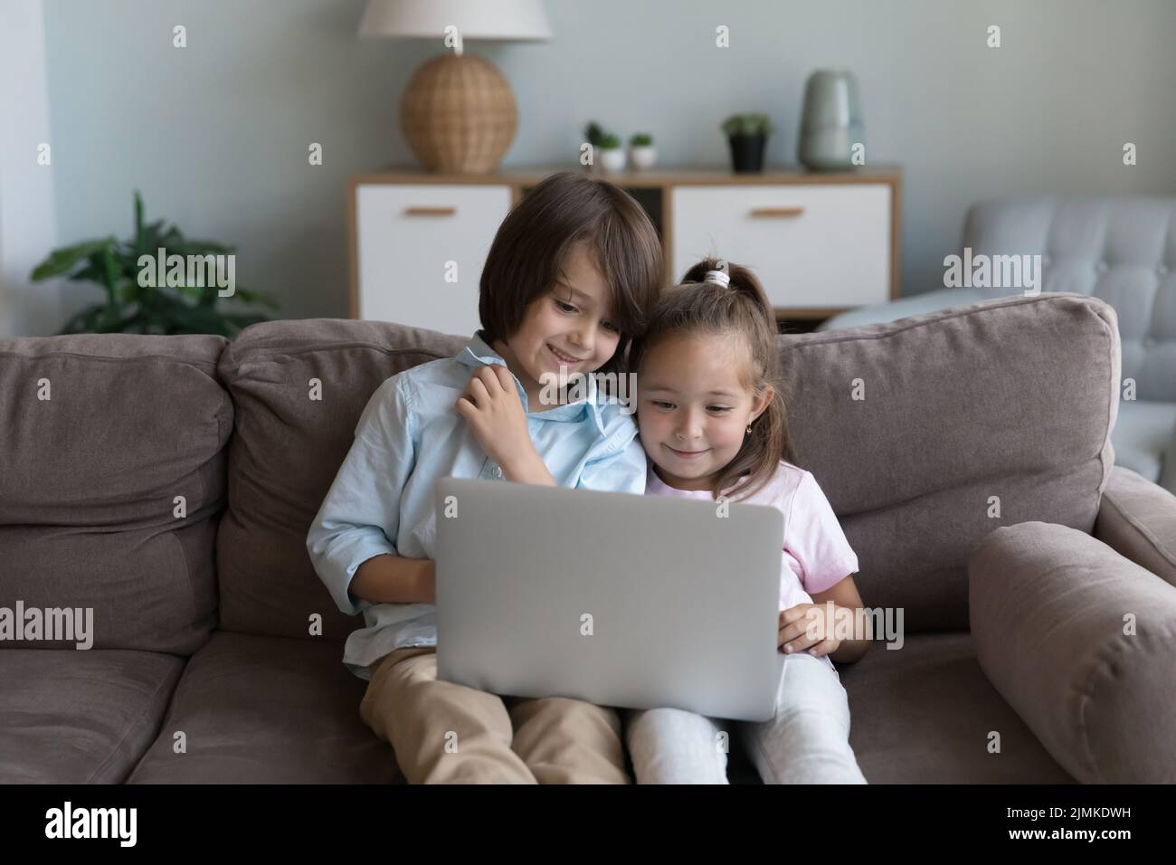 Children sit on couch spend time on internet using laptop Stock Photo ...