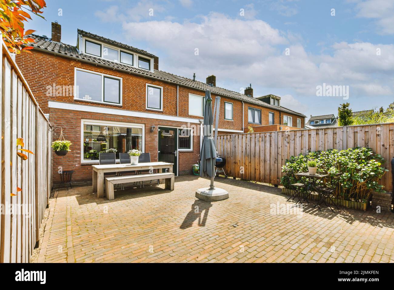 Neat paved patio with sitting area and small garden near wooden fence ...