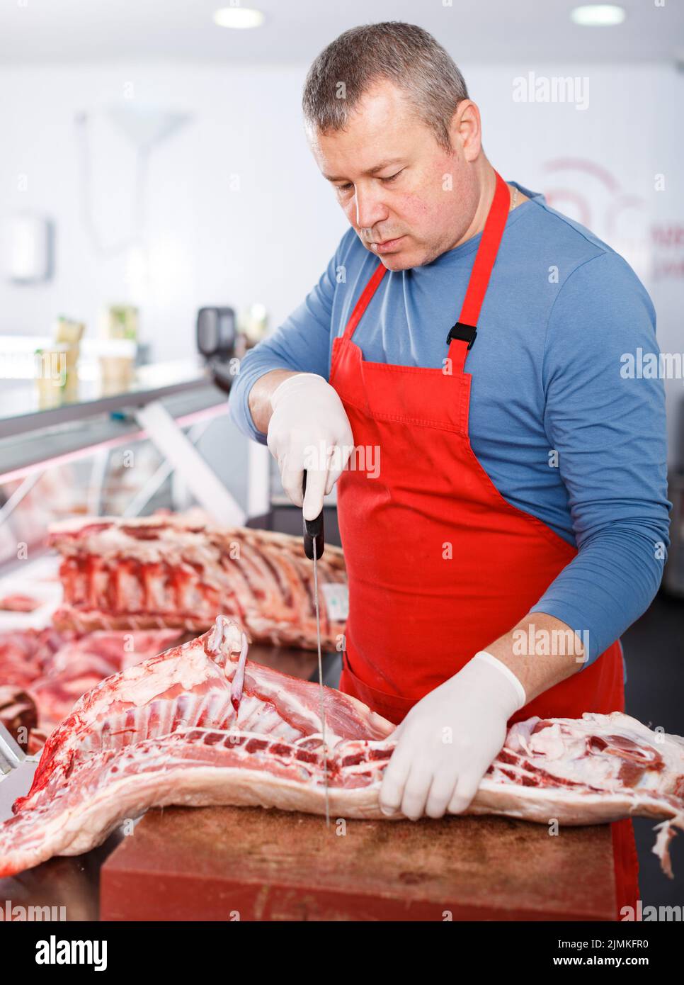 Serious seller splitting of pig carcass in shop Stock Photo - Alamy