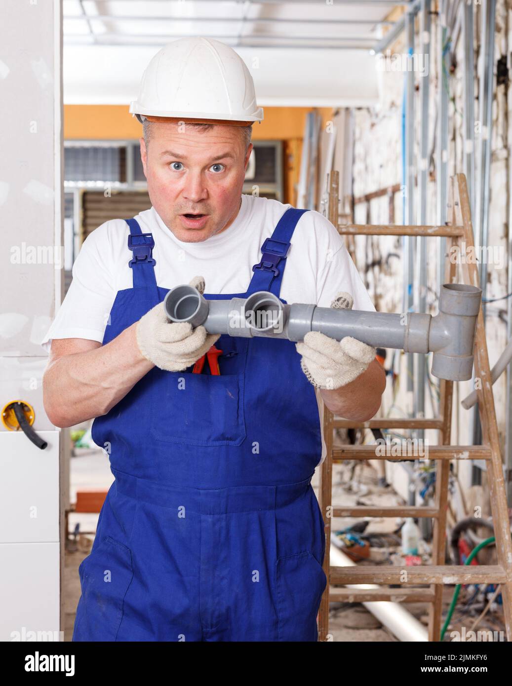 Puzzled builder with plastic pipes Stock Photo - Alamy