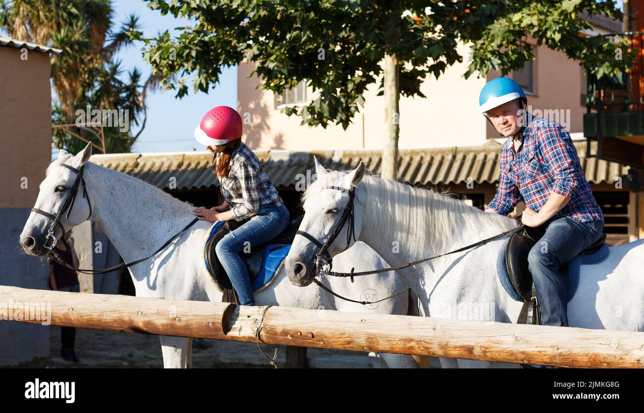 Mature couple in helmets learn to riding horse at farm outdoor Stock ...