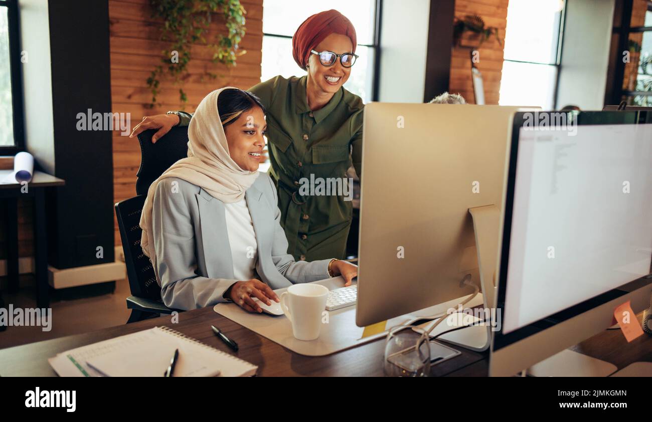 Two Muslim businesswomen having a discussion while looking at a ...