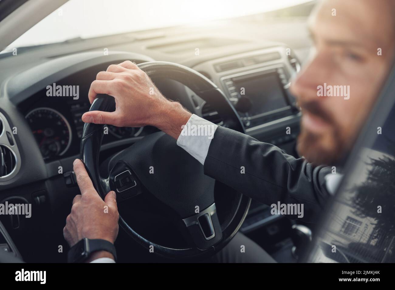 Handsome businessman in grey suit is riding behind steering wheel of ...