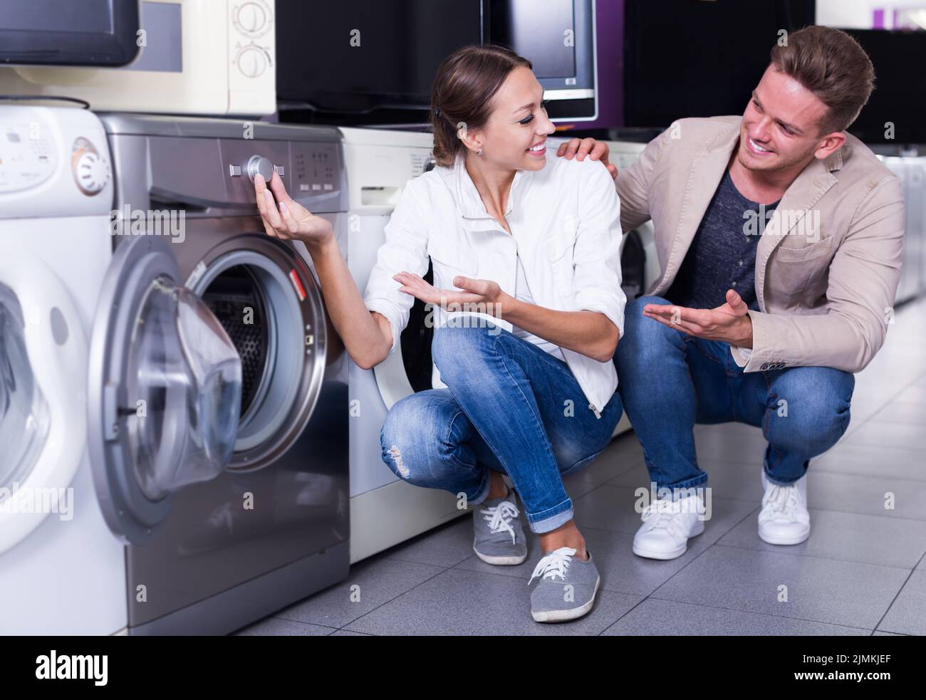 Smiling family selecting new clothes washer Stock Photo - Alamy