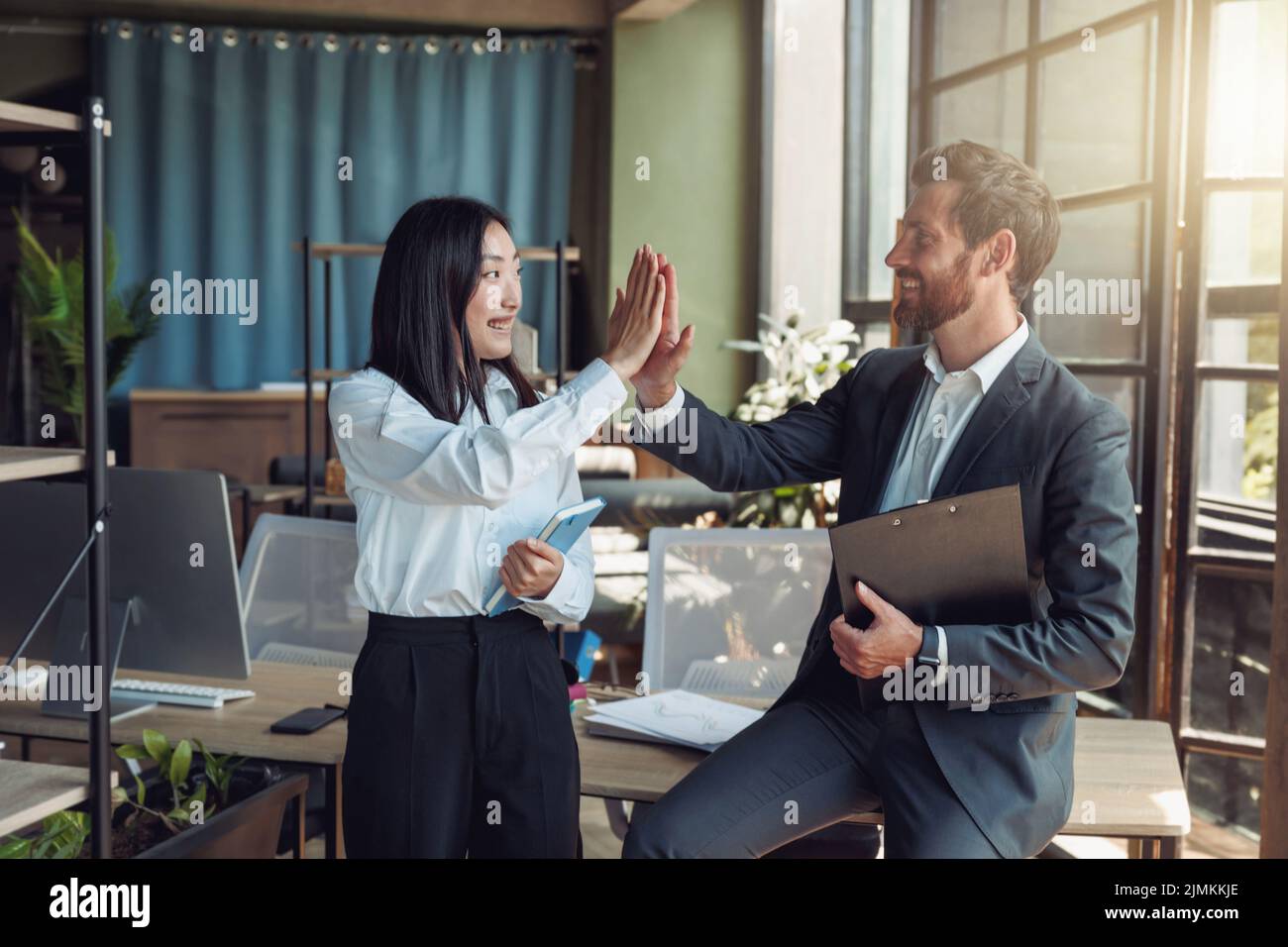 Two happy business colleagues clap hands after finishing work on ...