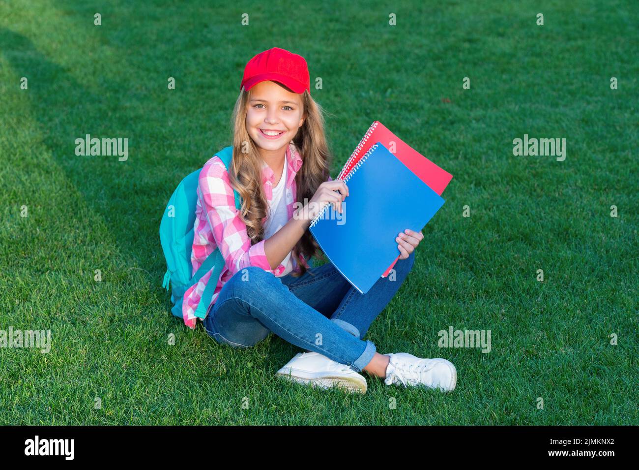 Happy teenage girl sitting on grass after school, back-to-school Stock ...