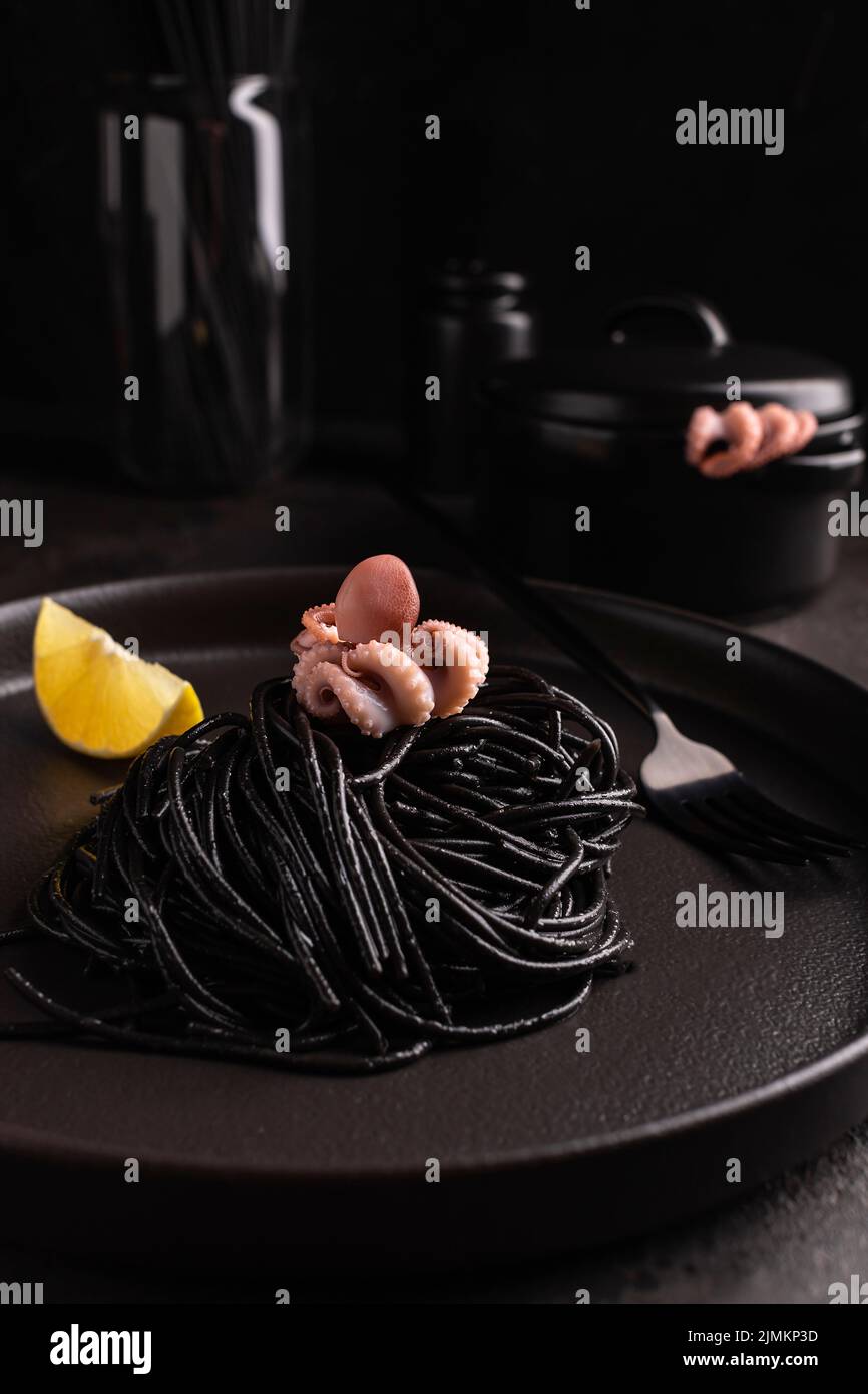 Black spaghetti with cuttlefish ink with boiled octopus Stock Photo - Alamy