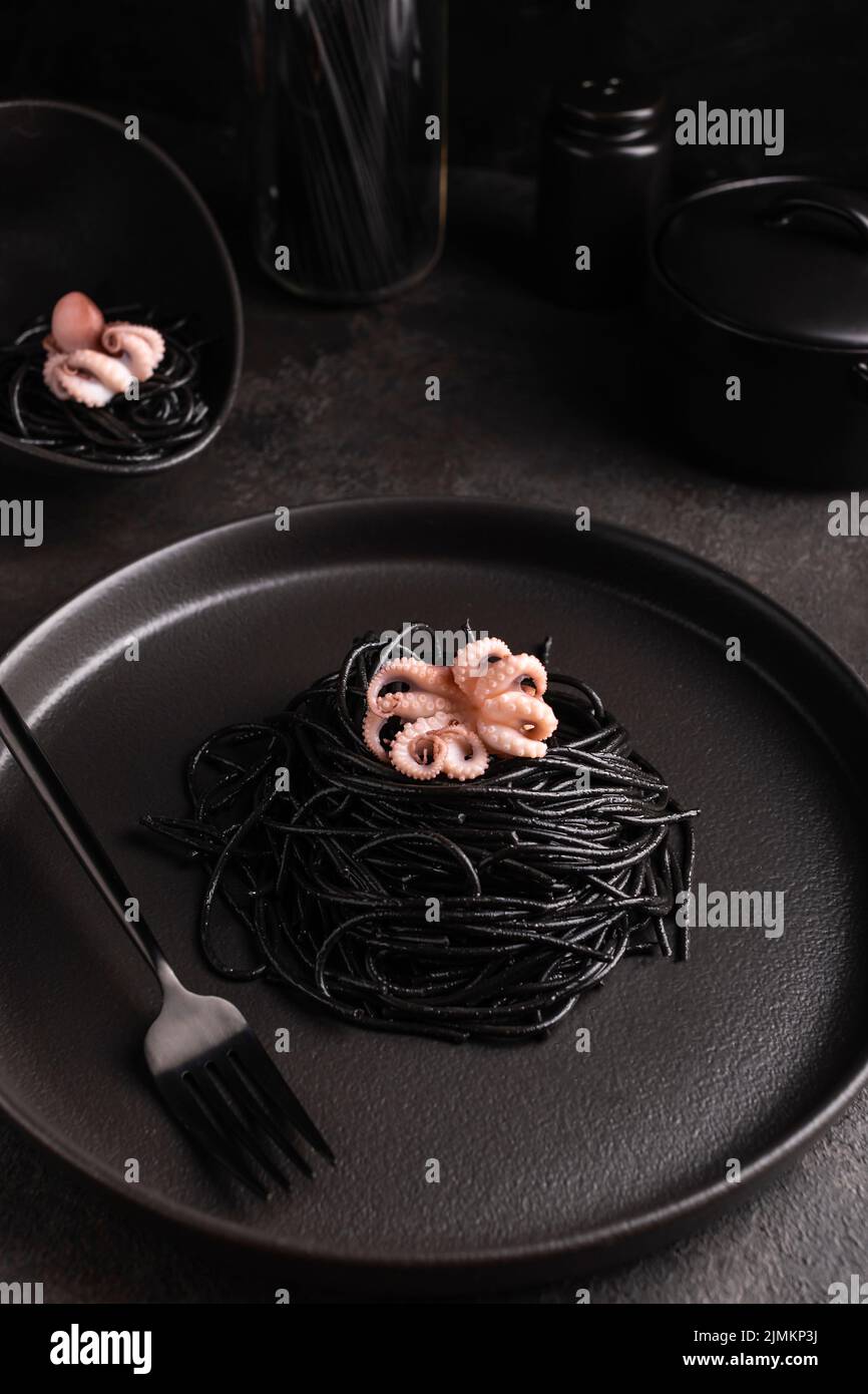 Black spaghetti with cuttlefish ink with boiled octopus Stock Photo - Alamy