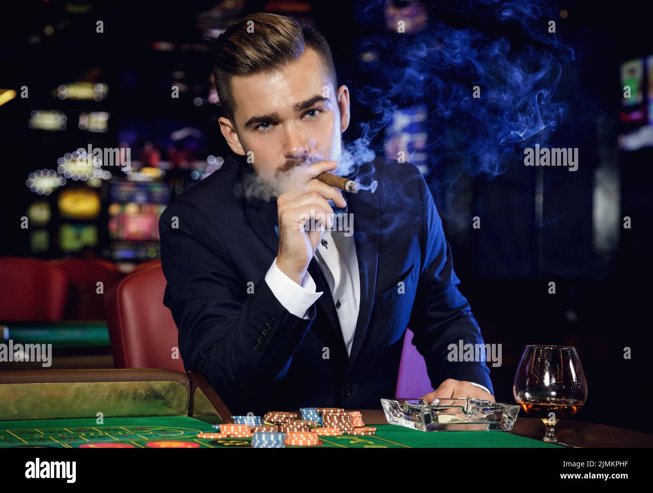 Rich handsome man smoking cigar in the casino Stock Photo - Alamy