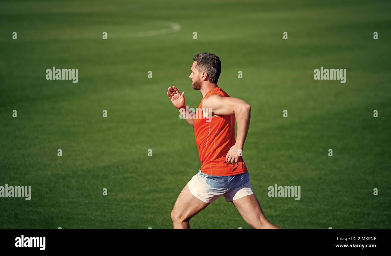 energetic athletic muscular man runner running outdoor on green grass ...