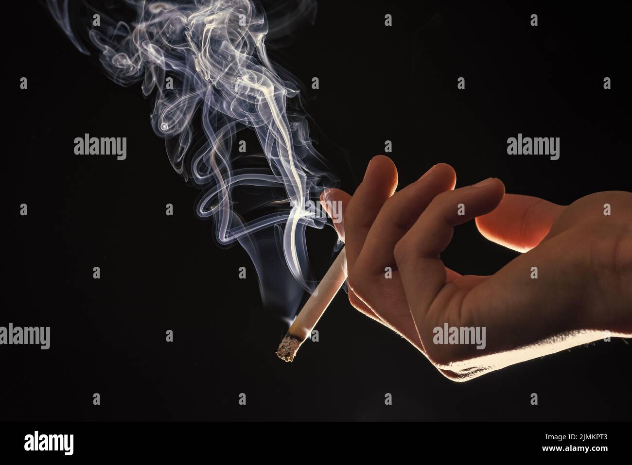 Male hand hold smoking cigarette with smoke stream dark background, bad ...