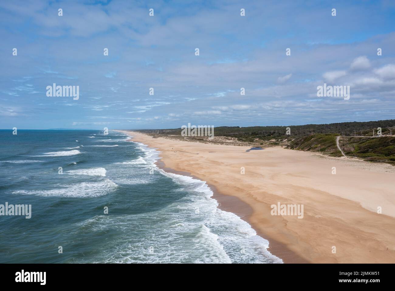 Drone view of a wide empty and endless golden sand beach with high sand ...