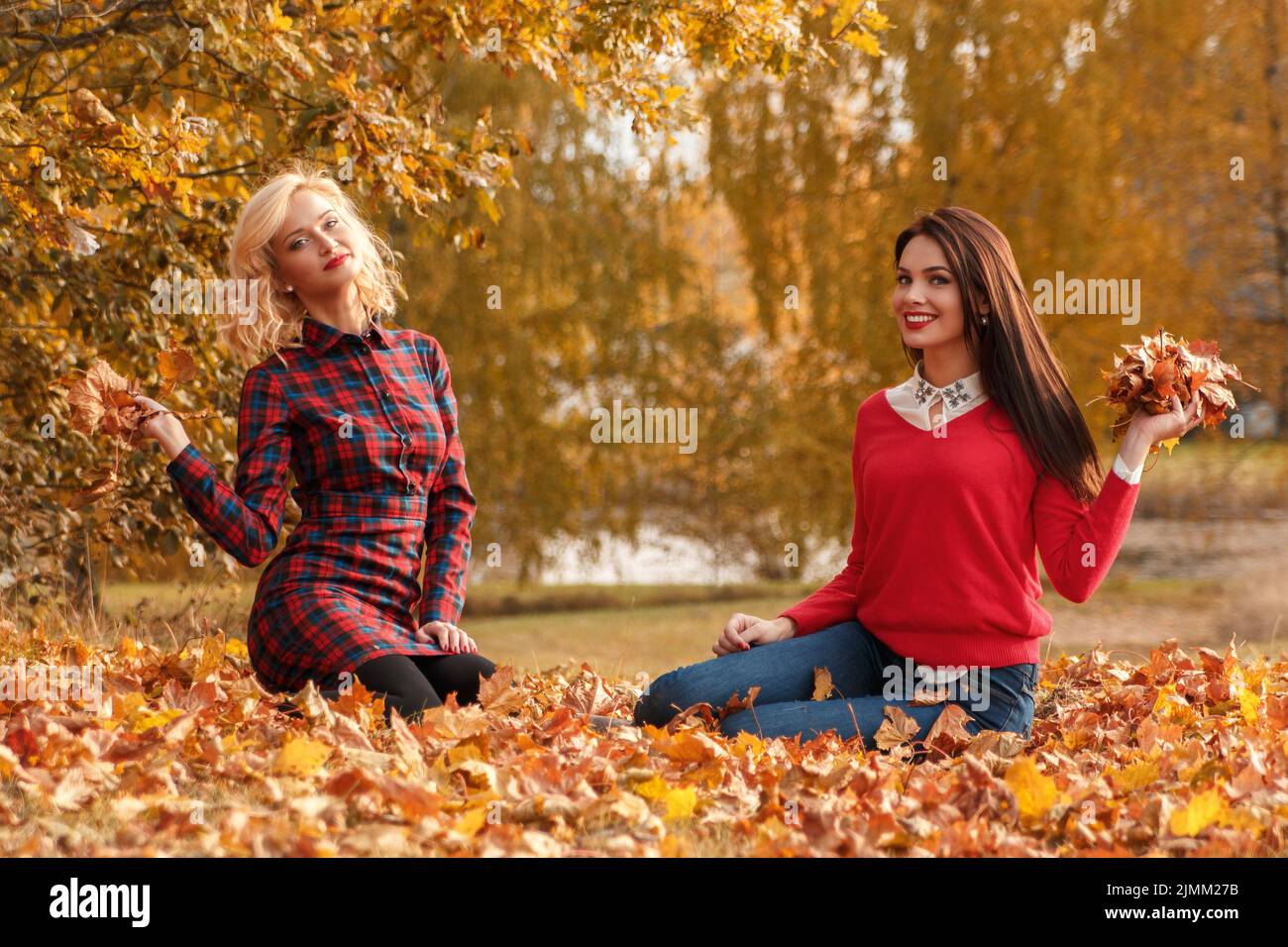 Two beautiful girls friends having fun in autumn park Stock Photo - Alamy