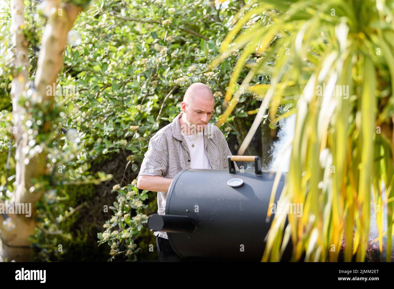 A bald Caucasian man grilling barbeque outdoors Stock Photo - Alamy