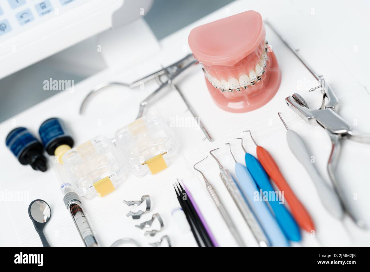 Tooth model with metal braces lying on a dental table with instruments ...