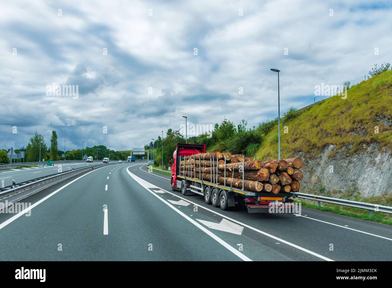 Truck loaded with wood logs entering a highway Stock Photo - Alamy