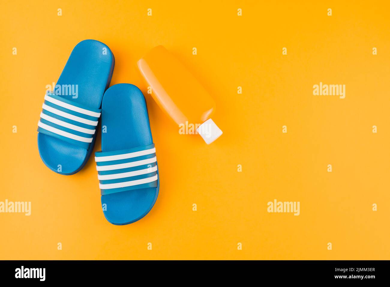 Blue flip flops with sunscreen lotion bottle yellow backdrop Stock ...
