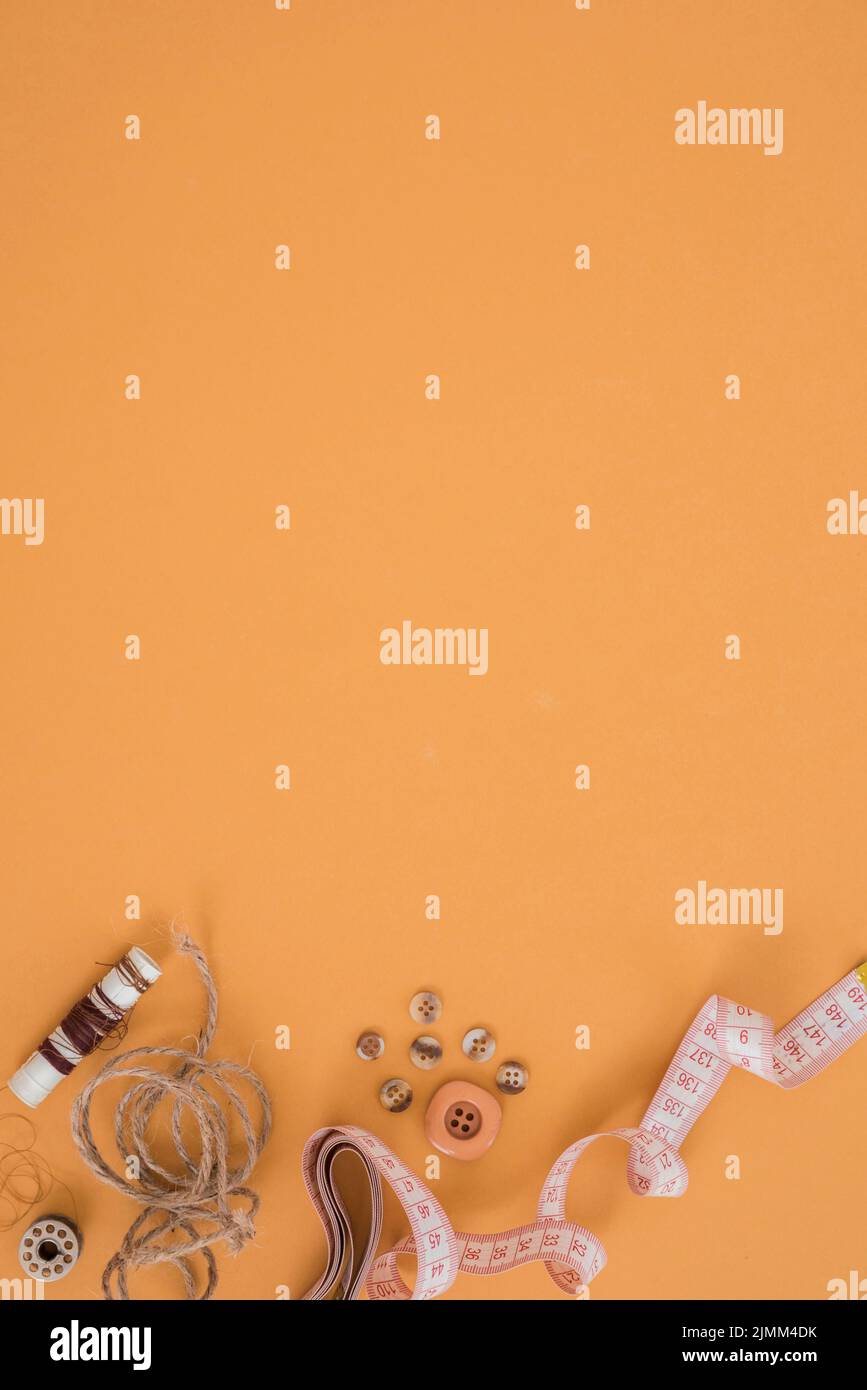 Spool jute string button measuring tape orange background Stock Photo ...