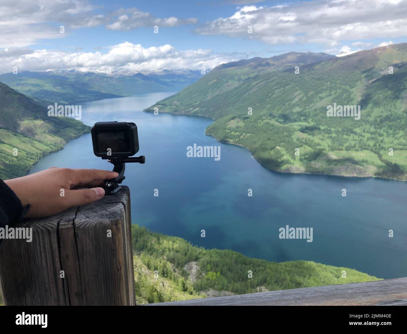 A male hand holding a camera and filming a landscape with mountains and ...