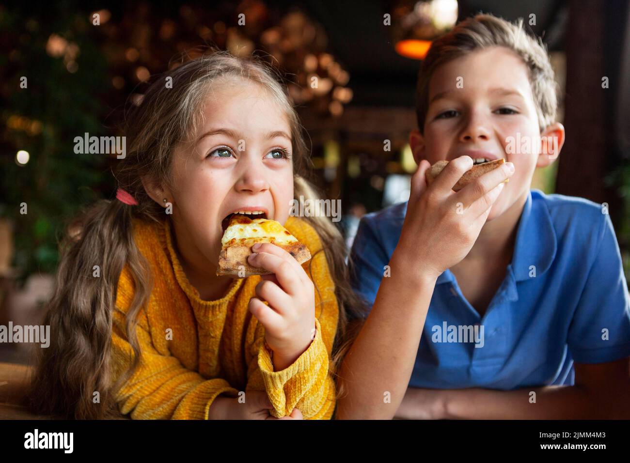 Medium shot smiley kids eating pizza Stock Photo - Alamy