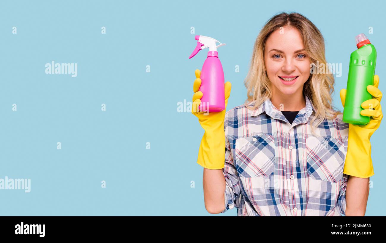 Front view happy woman looking camera holding spray bottle detergent ...