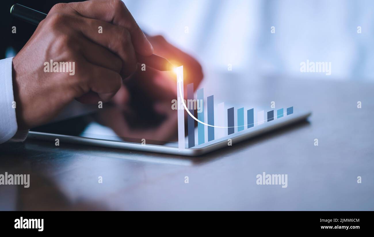 Businessman writing analyze graph for trade stock market on tablet ...