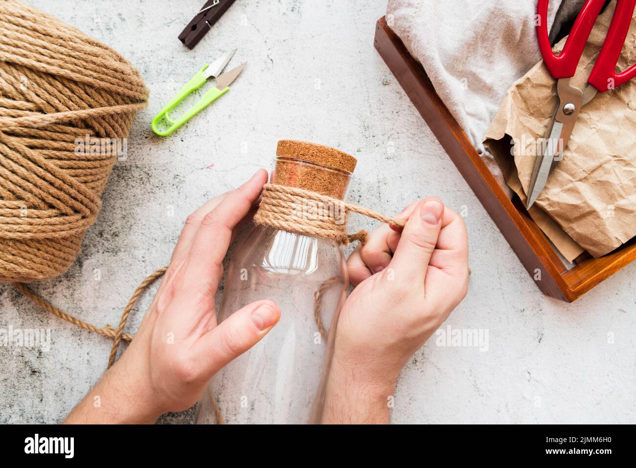 Close up person wrapping jute string glass bottle white textured ...