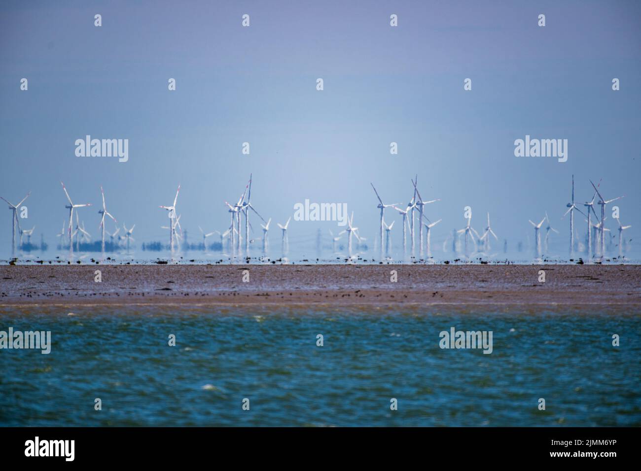 Windturbines stand over heat mirage behind a sandbank in the North Sea ...