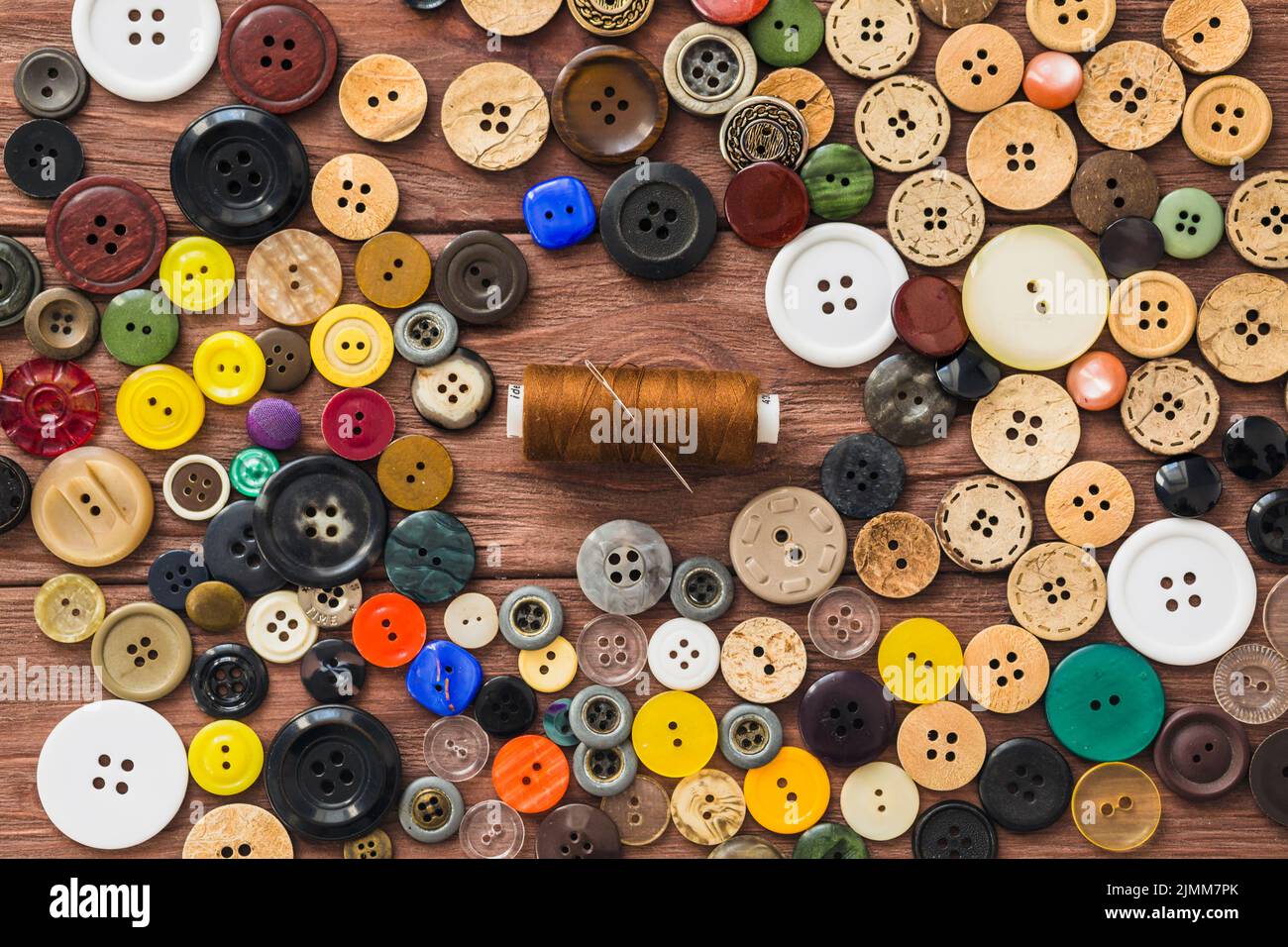 Many colorful buttons brown thread needle wooden background Stock Photo ...