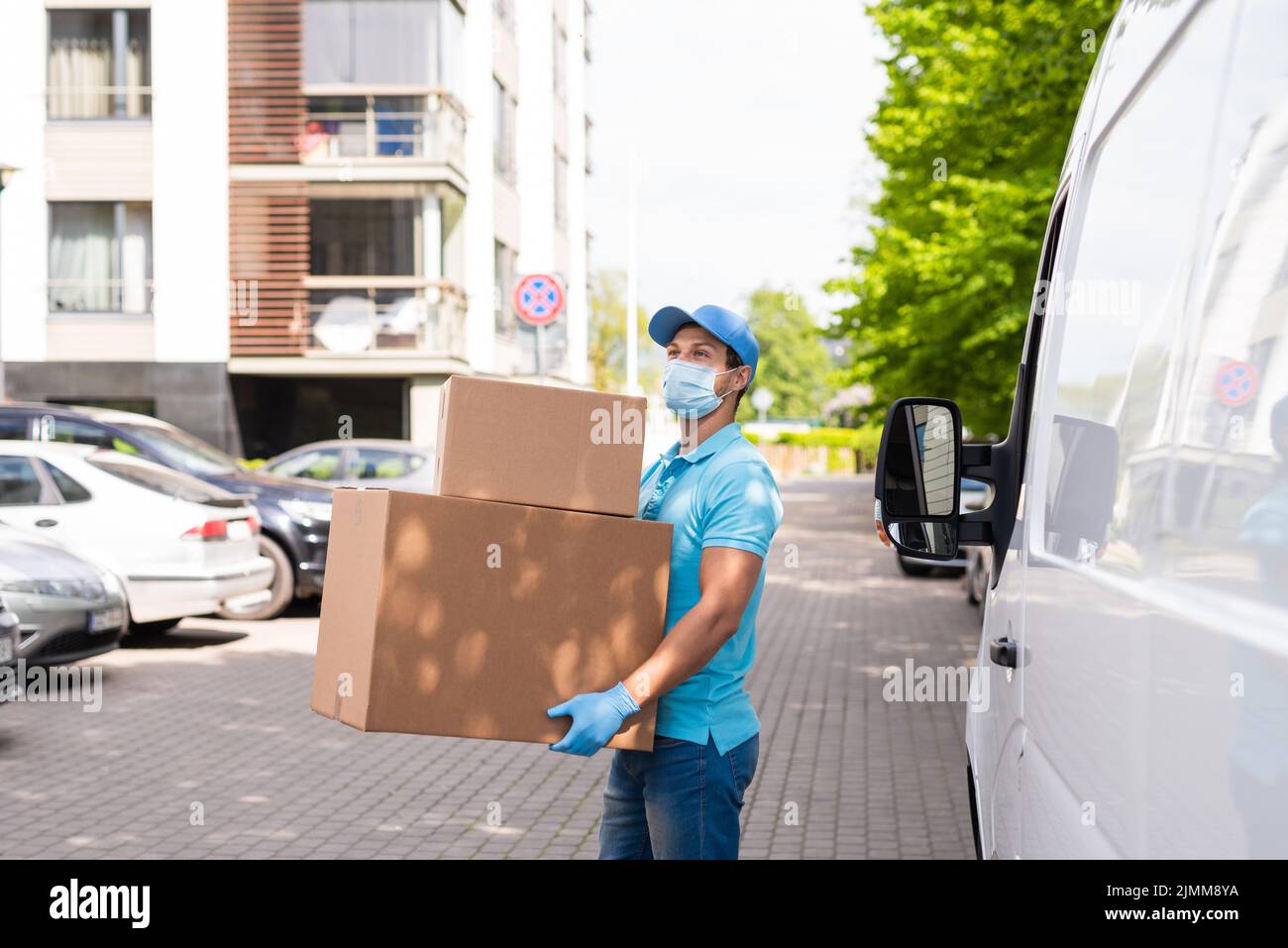 Delivery man wearing prevention mask and gloves is holding stack of the ...