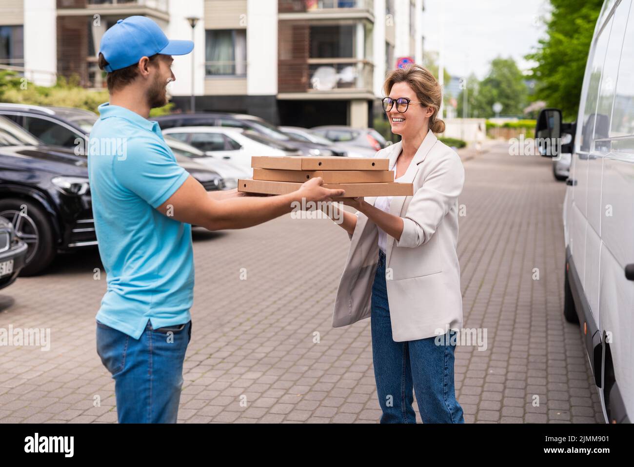 Delivery man wearing blue uniform delivers pizza to a woman client ...