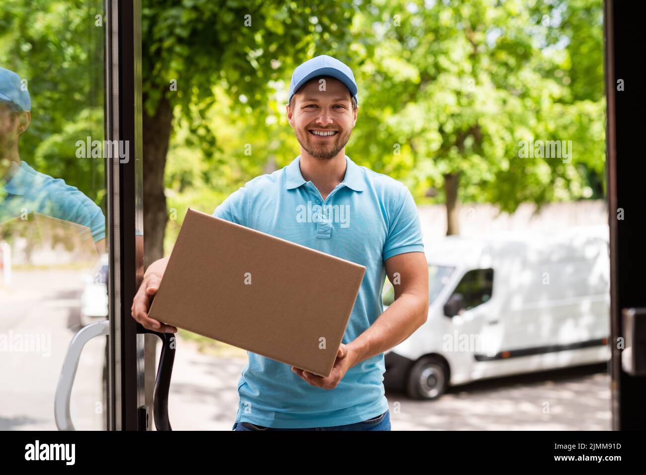 Smiling courier bring a package in the cardboard box to your house ...