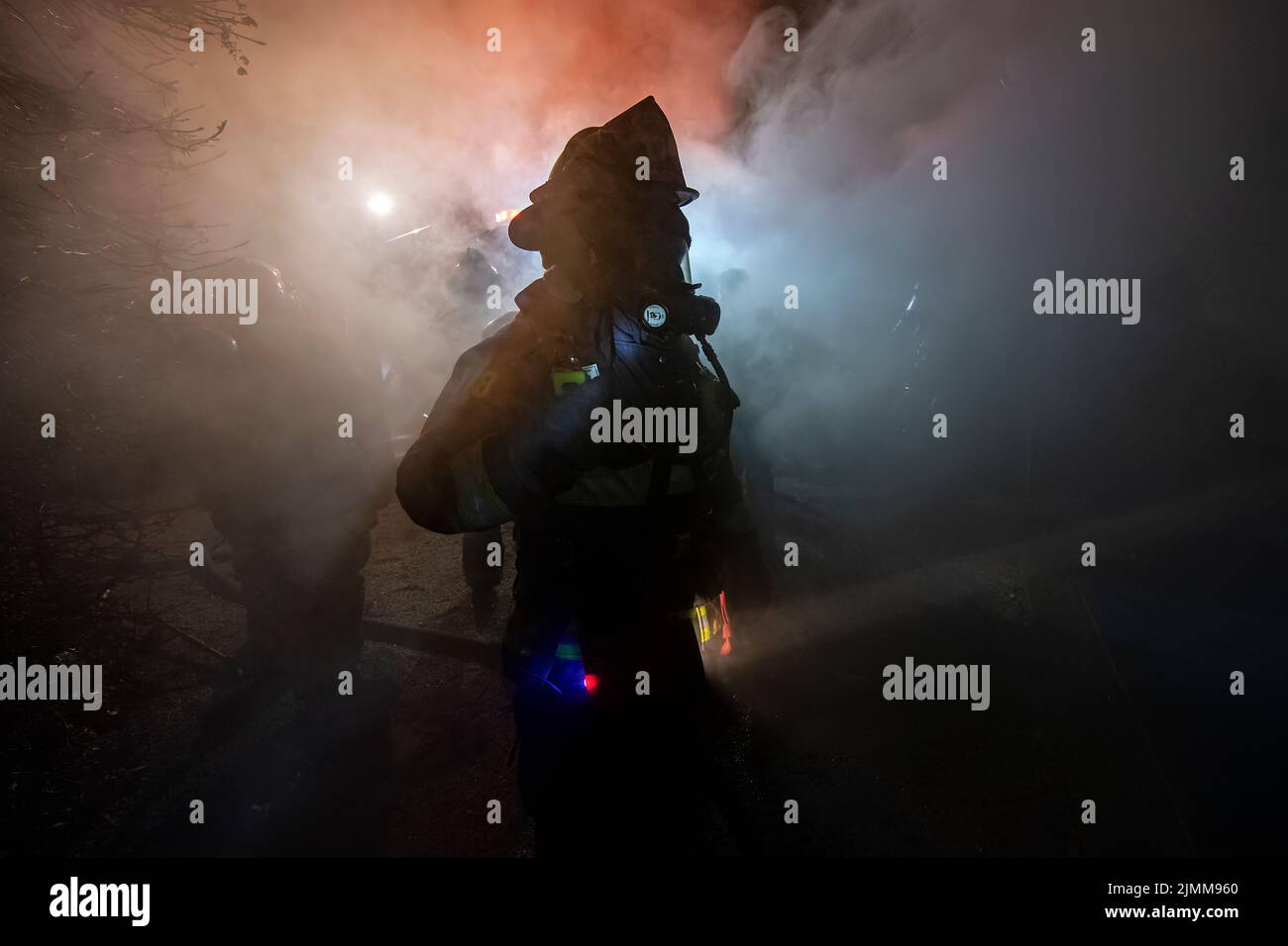 A firefighter wearing breathing apparatus is silhouetted as he waits in ...