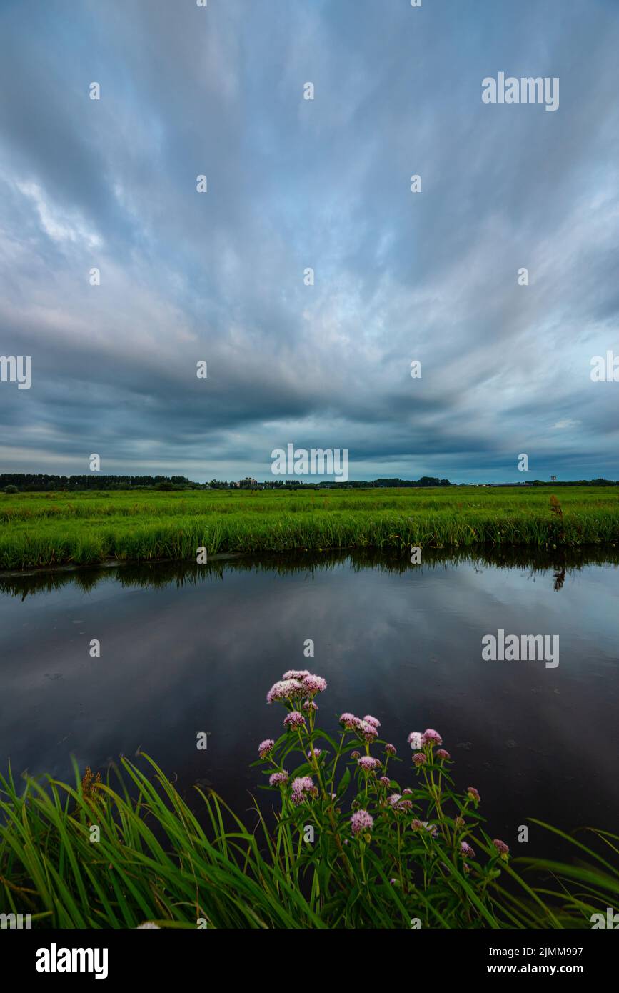 Dramatic clouds are reflected in a water filled ditch in the Dutch ...