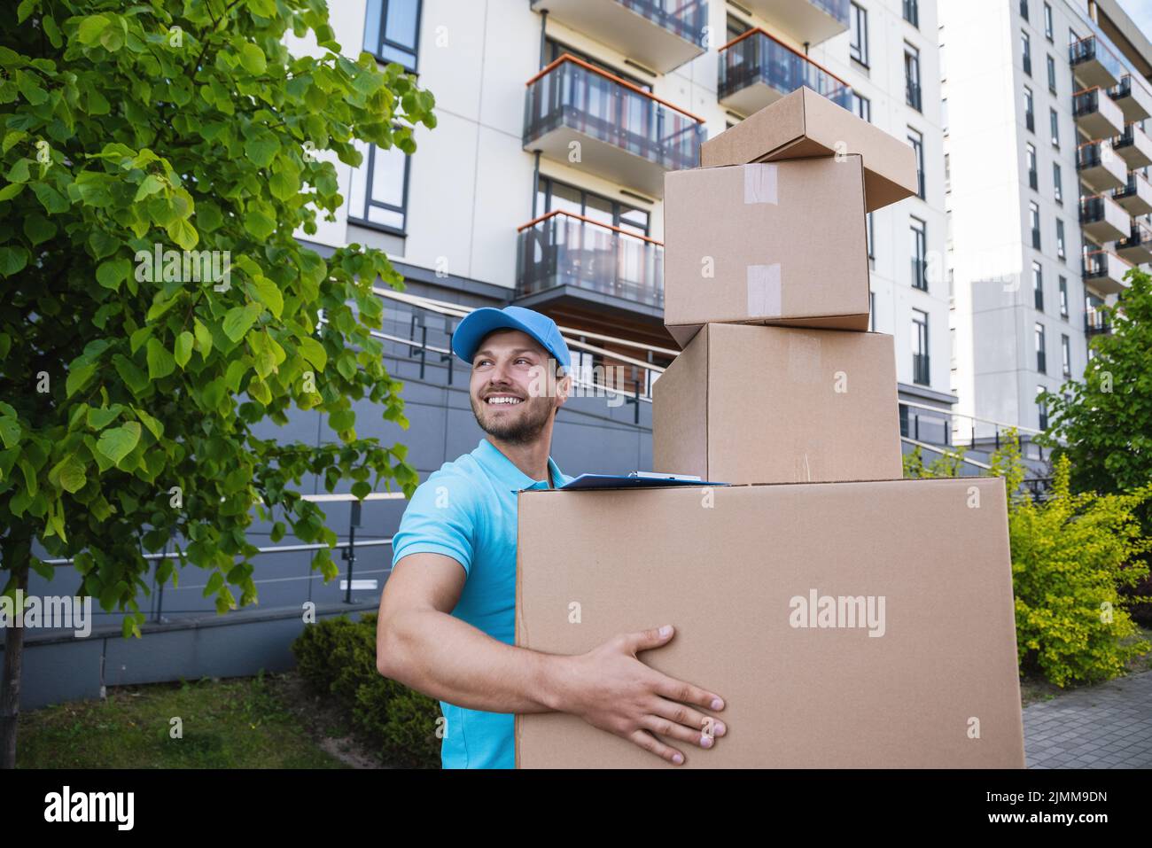 Strong delivery man holding a stack of a cardboard boxes Stock Photo ...