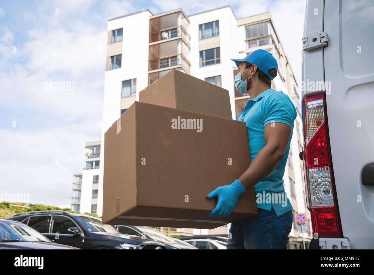Delivery man wearing prevention mask and gloves is holding stack of the ...