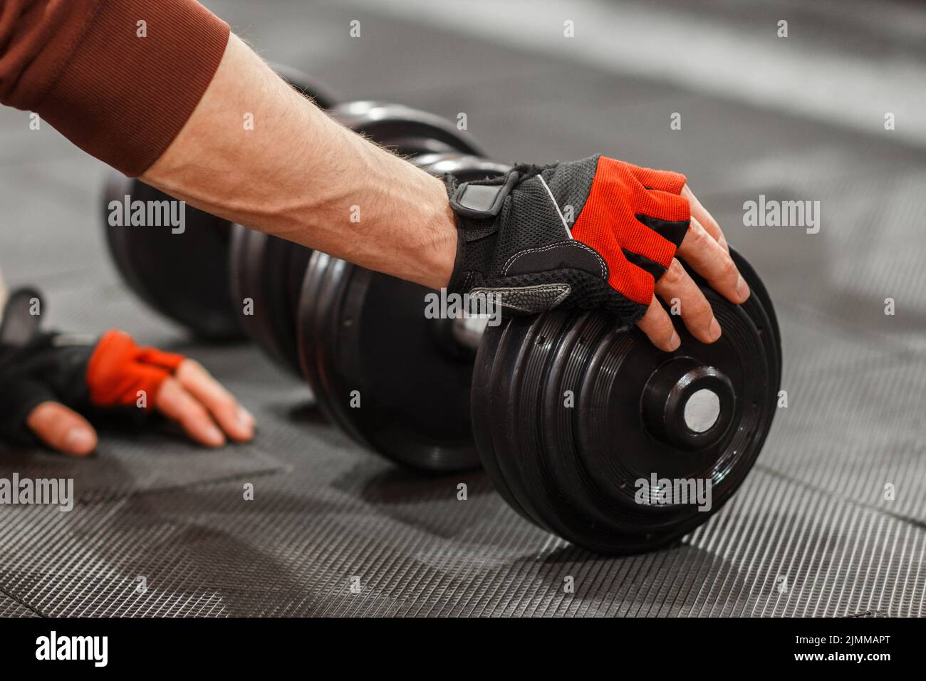 Male hand touching dumbbell on gym floor closeup Stock Photo - Alamy