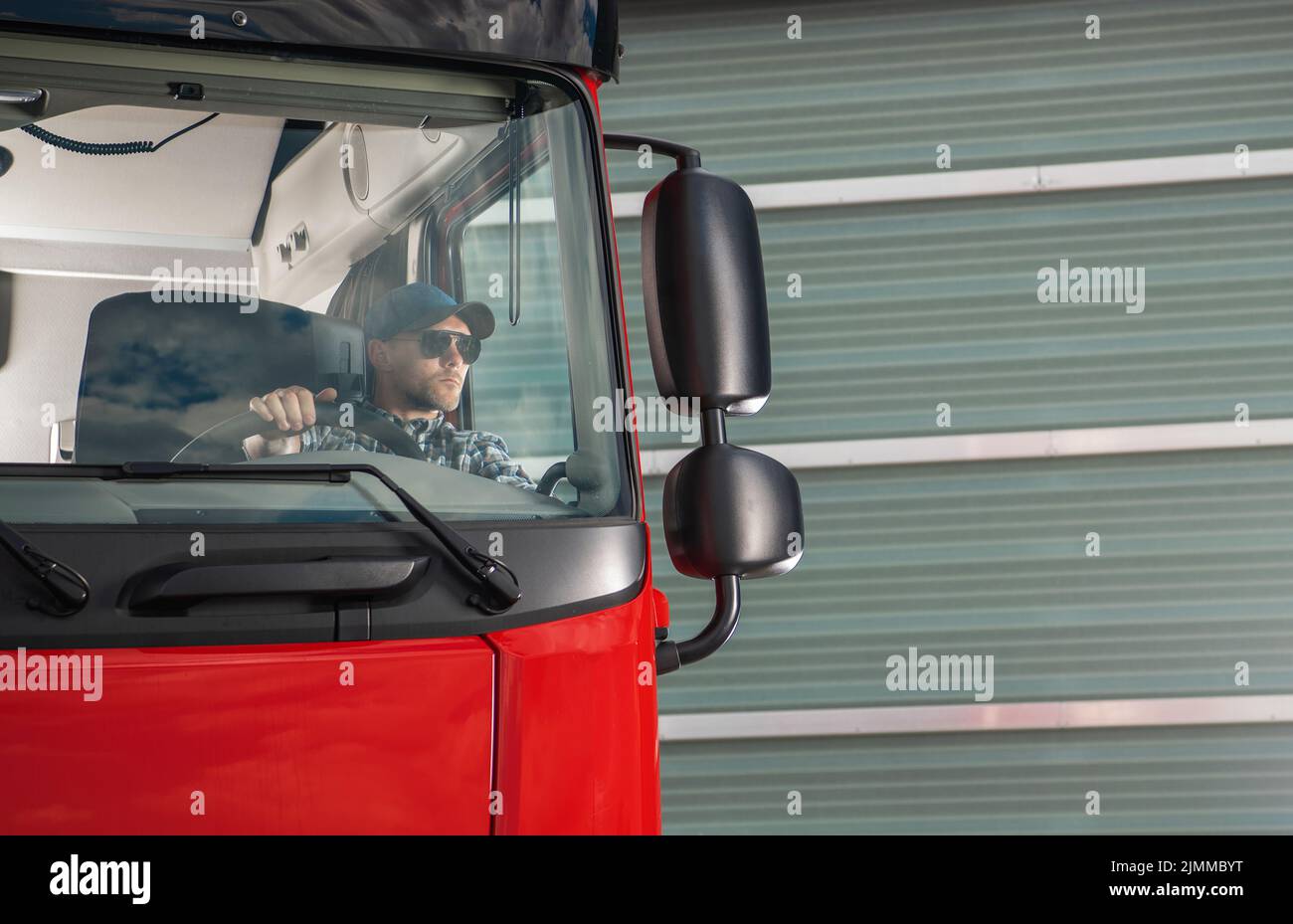 Caucasian Truck Driver in Sunglasses and Baseball Cap Driving His Red ...