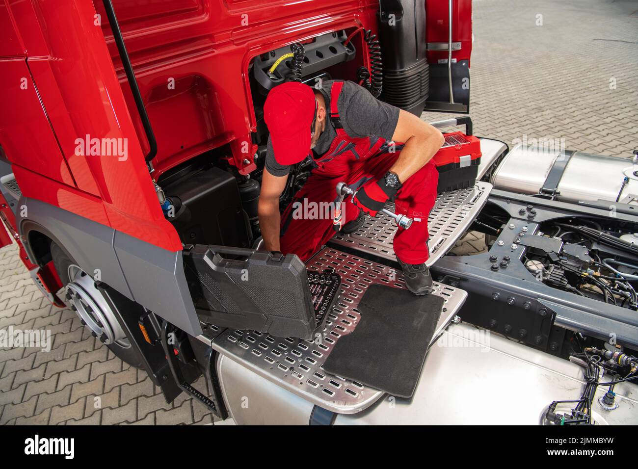Caucasian Heavy Duty Vehicle Engineer Sitting on the Back of a Red Semi ...