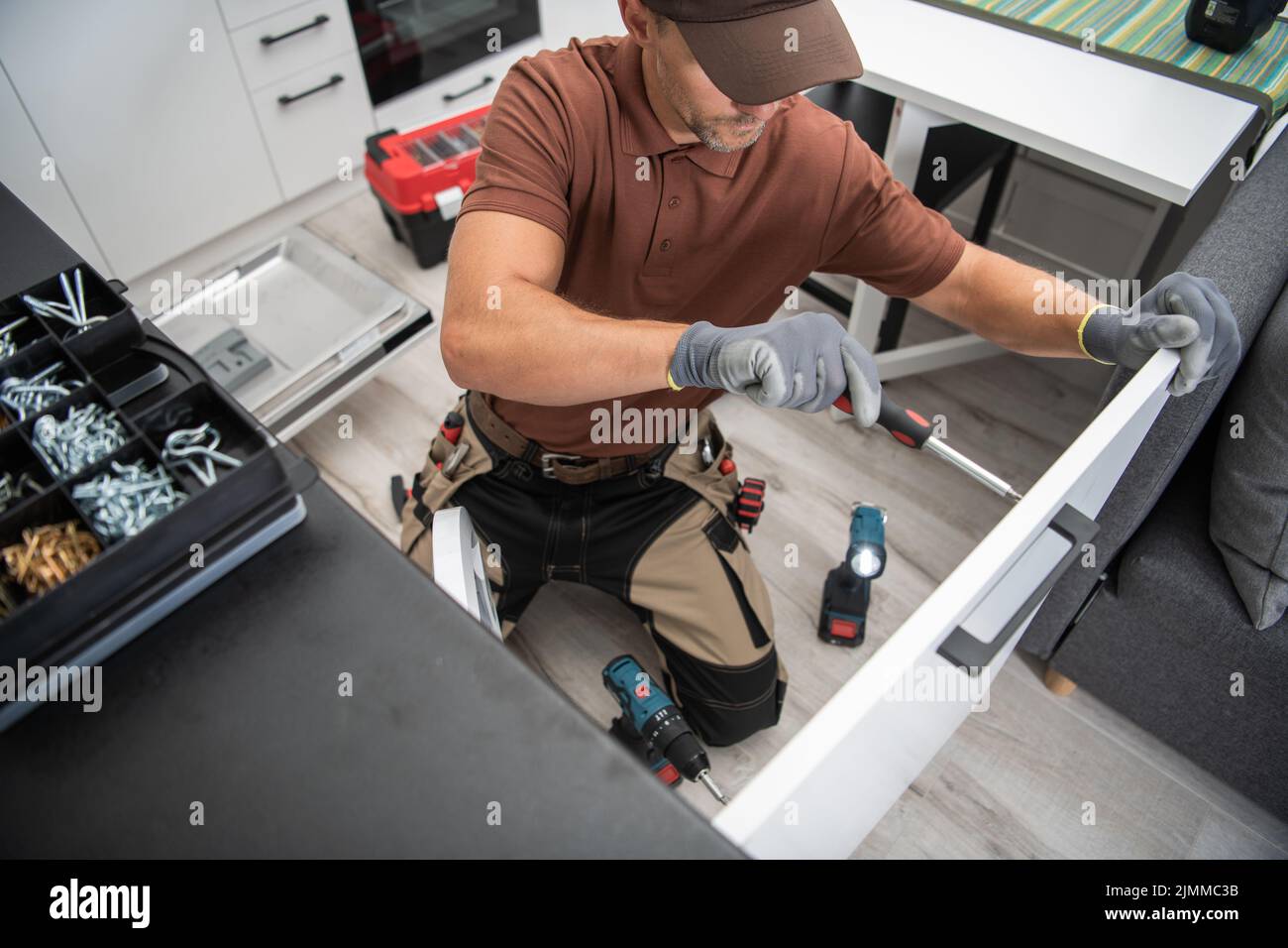 Caucasian Male Worker Installing the Handle to the Kitchen Cabinet Door ...