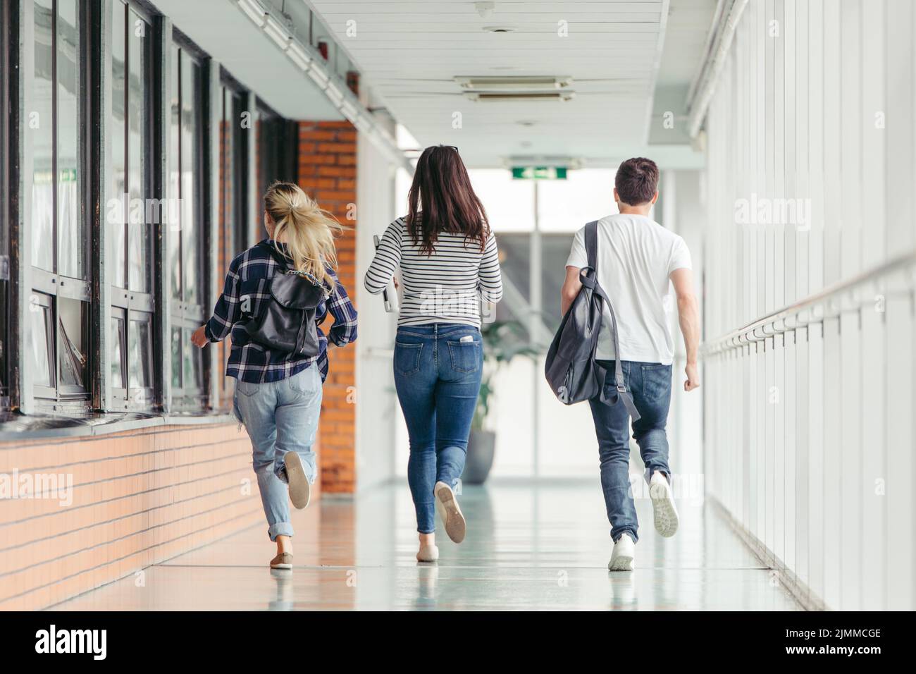 Friends running college hall Stock Photo - Alamy